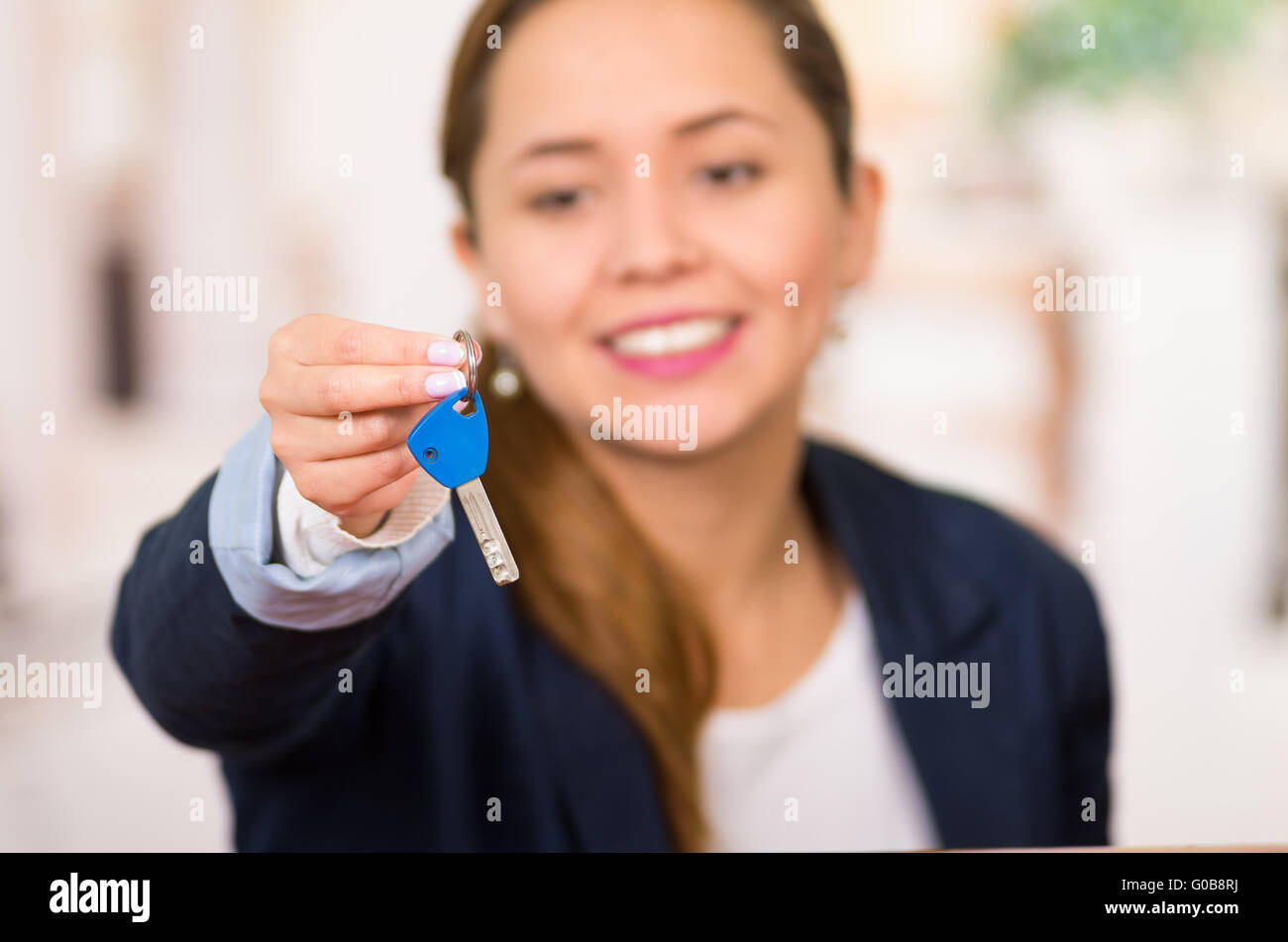 Young brunette hotel receptionist with friendly smile handing over key ...