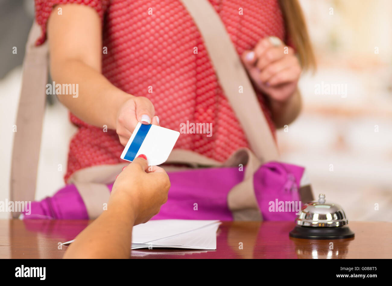 Closeup customer guest and hotel receptionist interacting at front desk ...