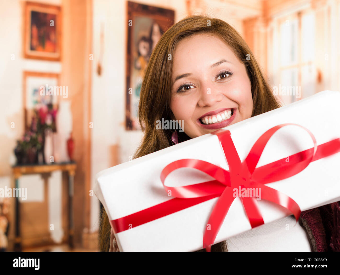 Brunette with beautiful smile holding up present happily posing for ...