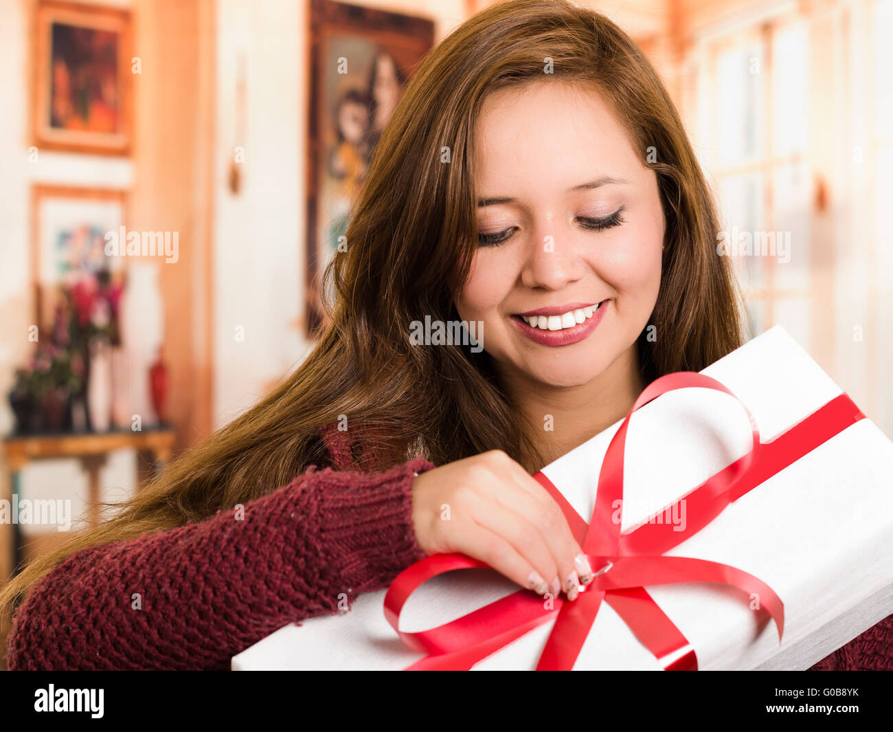 Brunette with beautiful smile holding up present happily posing for ...