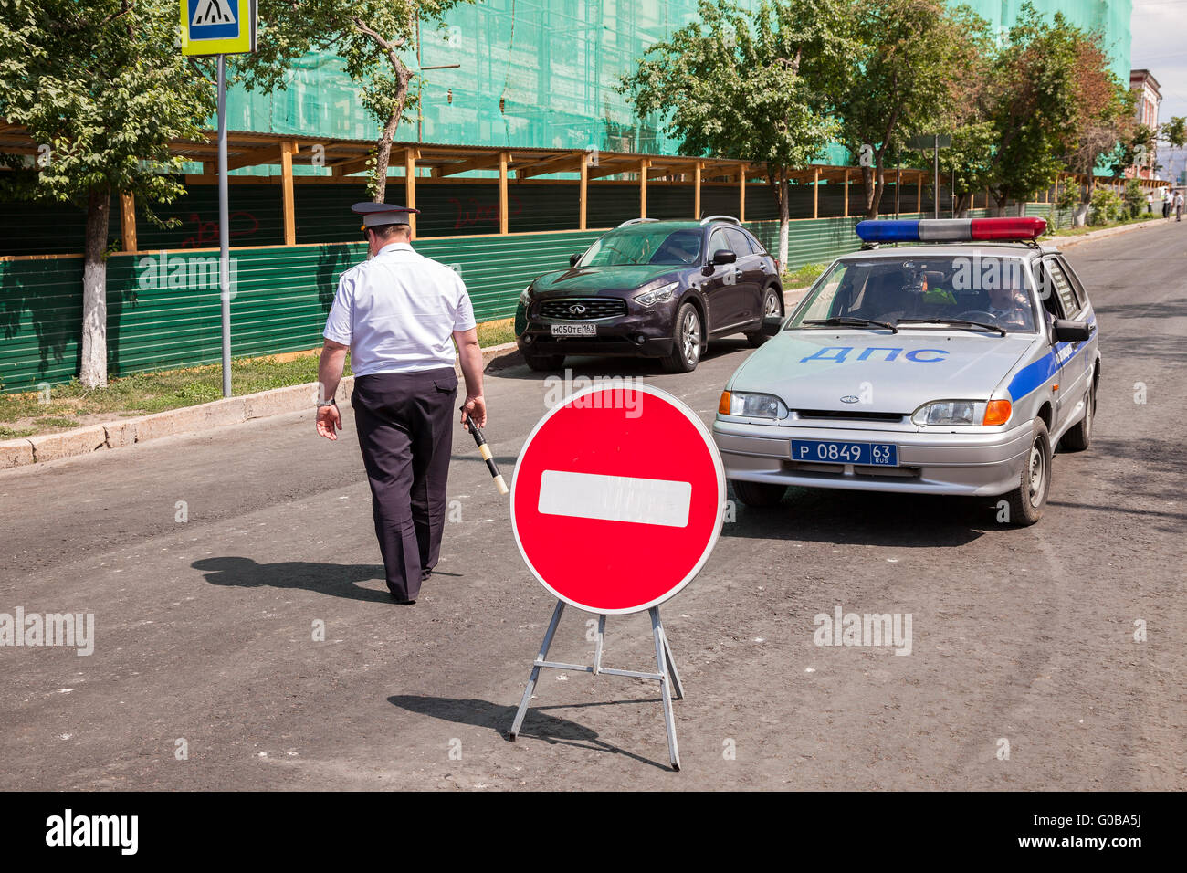Russian police officer and patrol vehicle parked at the street in ...