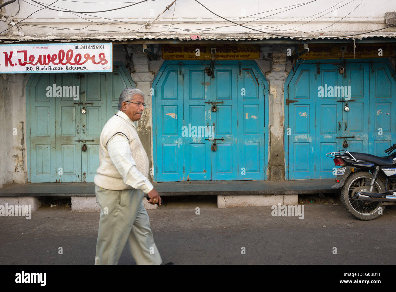 Man walking past closed shop fronts in old town Udaipur Stock Photo - Alamy
