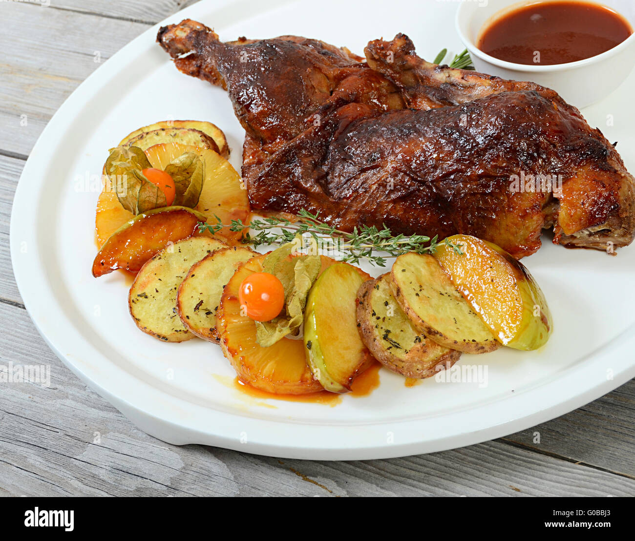The baked half of duck with a potato, apples and pineapple Stock Photo ...