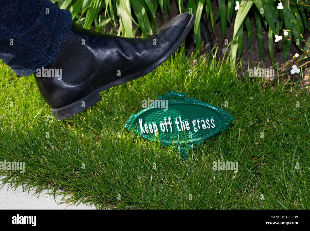A 'Keep off the Grass' sign with a foot nearby Stock Photo - Alamy