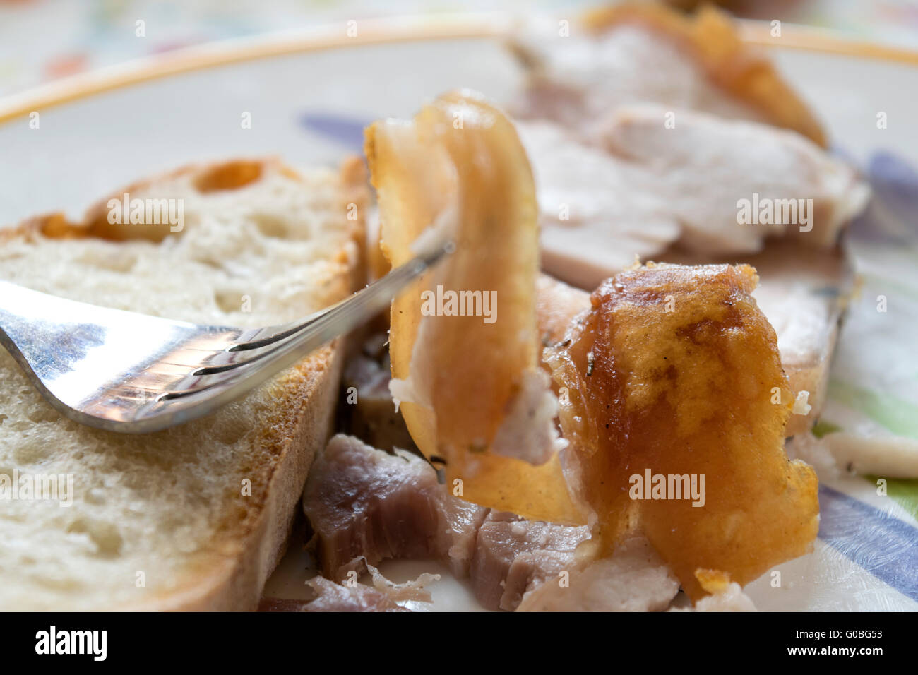 toasted and crispy pork rind of a roman porchetta with a slice of bread ...