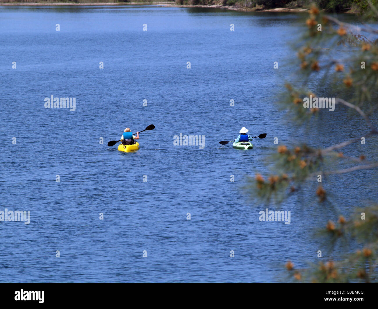 Yellow and green kayaks on blue lake Stock Photo - Alamy