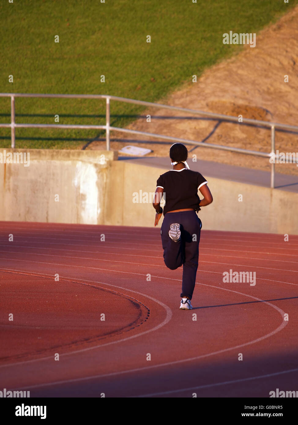 Young black woman running on track in sweats Stock Photo - Alamy
