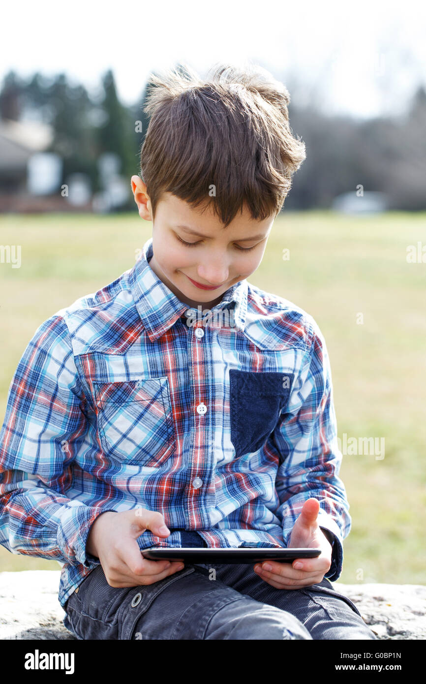 Little boy playing on tablet outdoor in park Stock Photo - Alamy