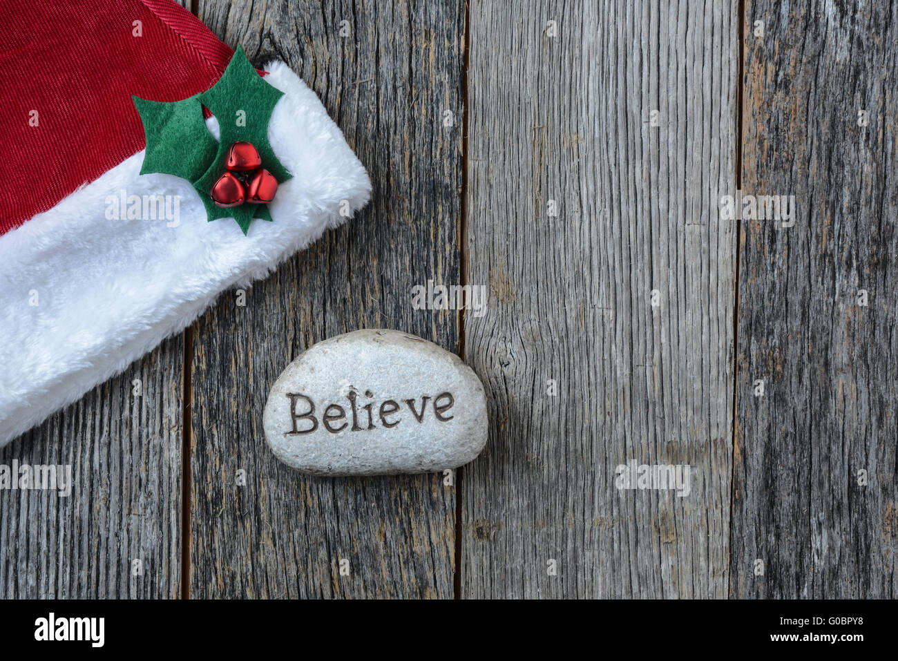 Santa Hat with the text Believe on a Stone Rock on Wood Background ...