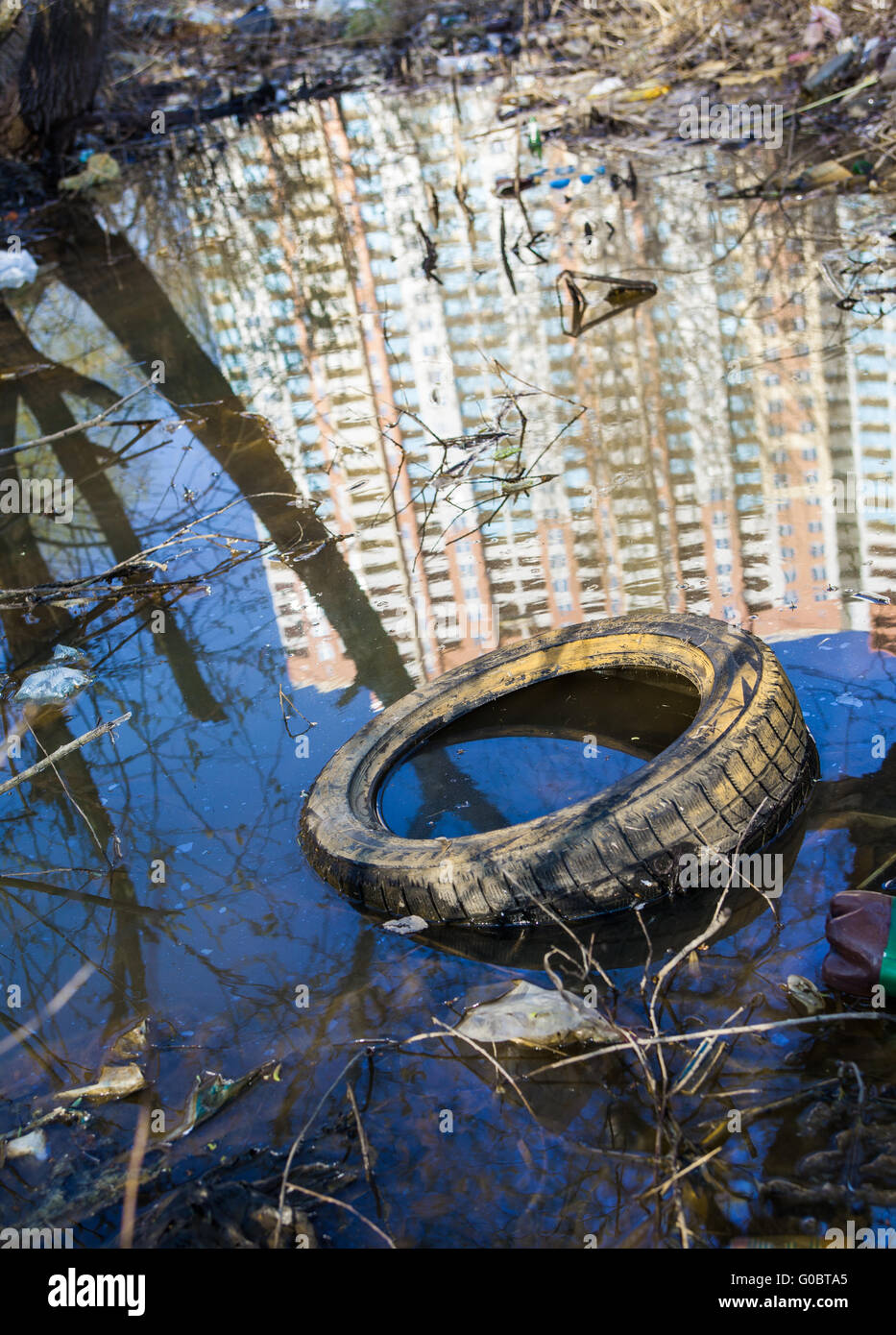 Garbage, old tire and reflection of the high-rise in the water Stock ...