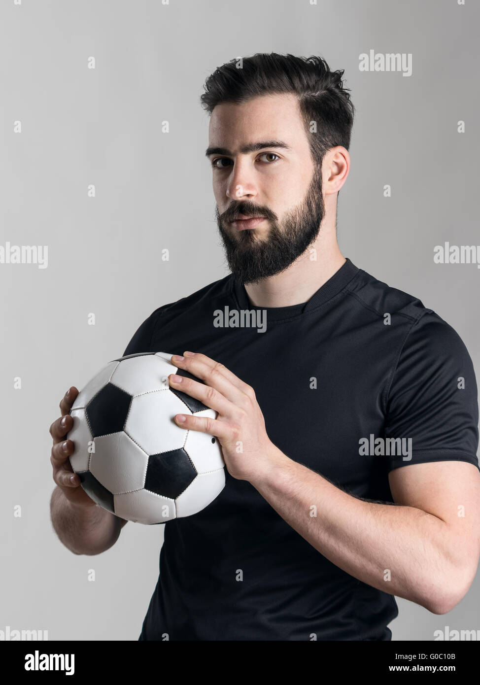Intense lighting portrait of serious soccer player holding ball looking ...