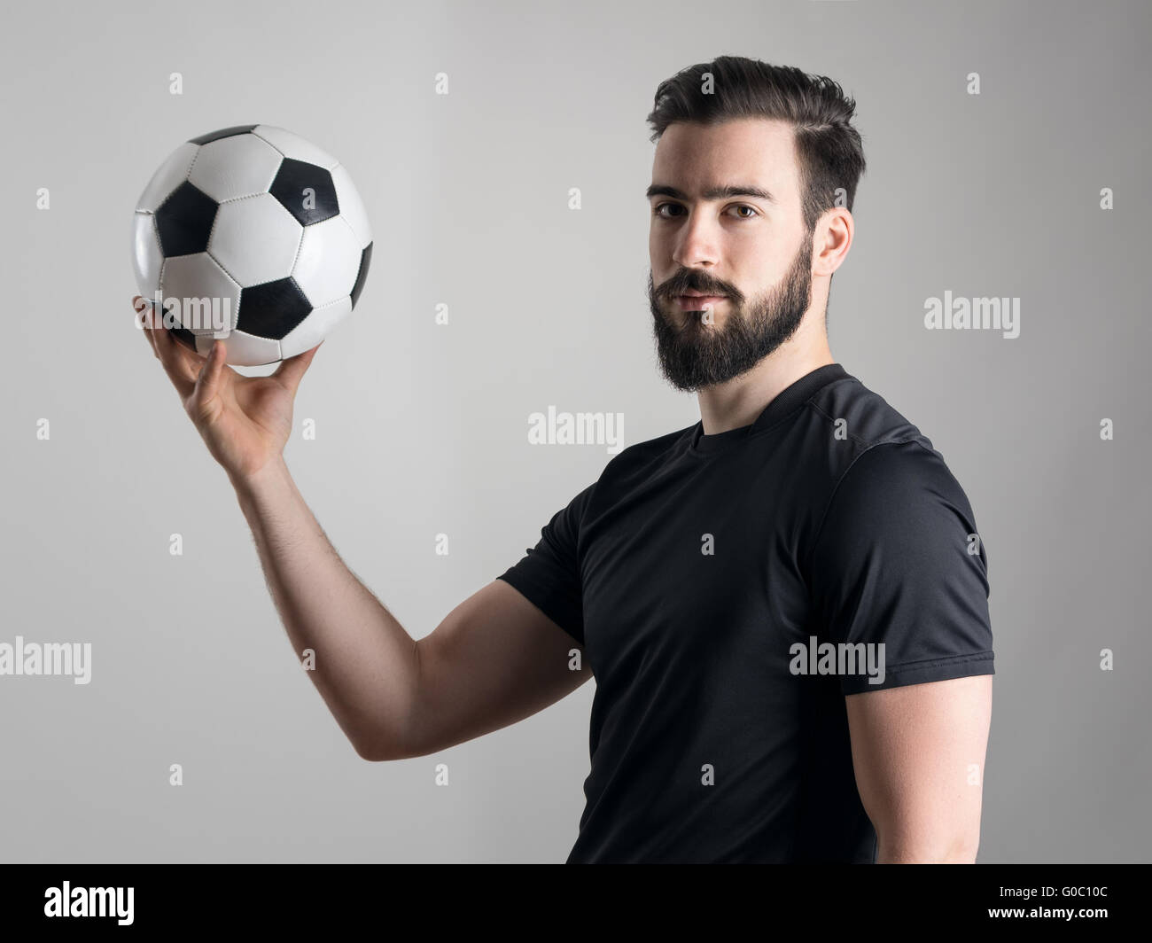 Side view of intense shadow portrait of soccer player holding ball ...