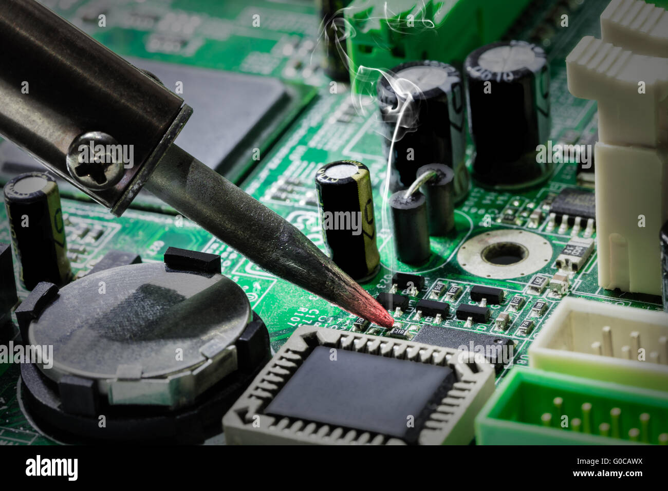 smoking soldering iron on a computer motherboard closeup Stock Photo ...
