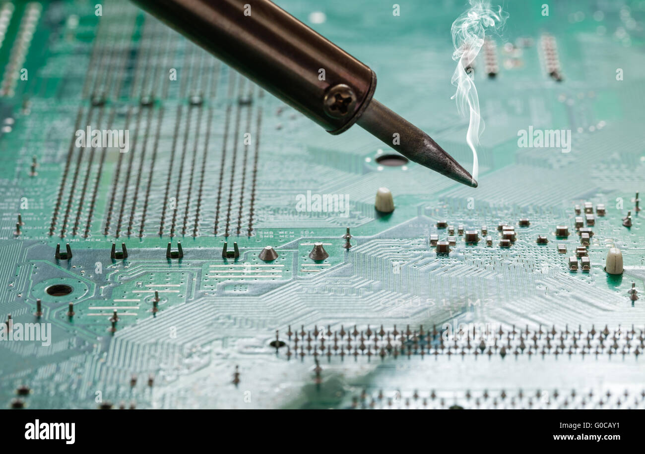 smoking soldering iron on a computer motherboard closeup Stock Photo ...