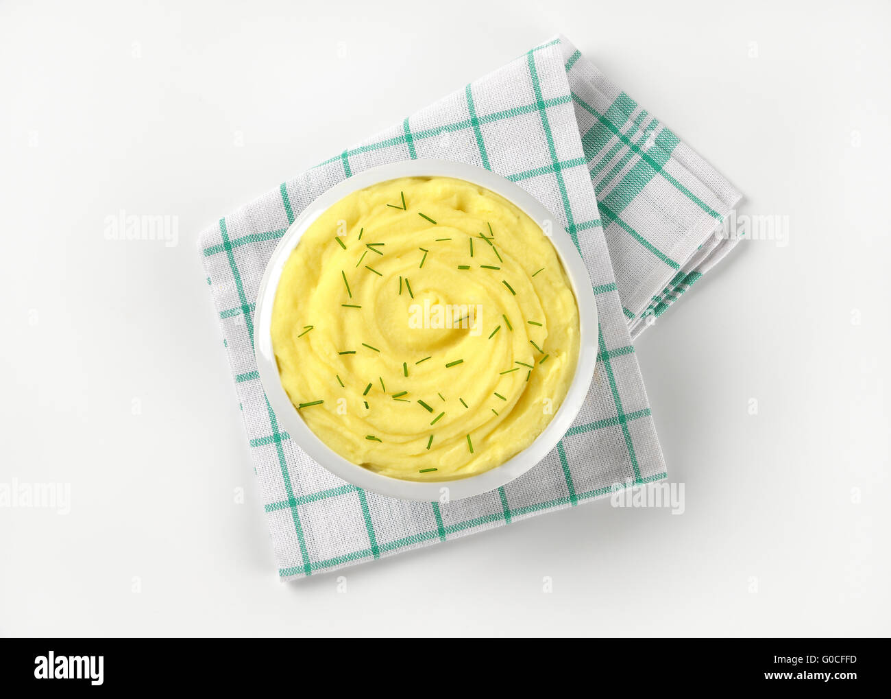 bowl of mashed potato puree with chopped chives on checkered dishtowel ...
