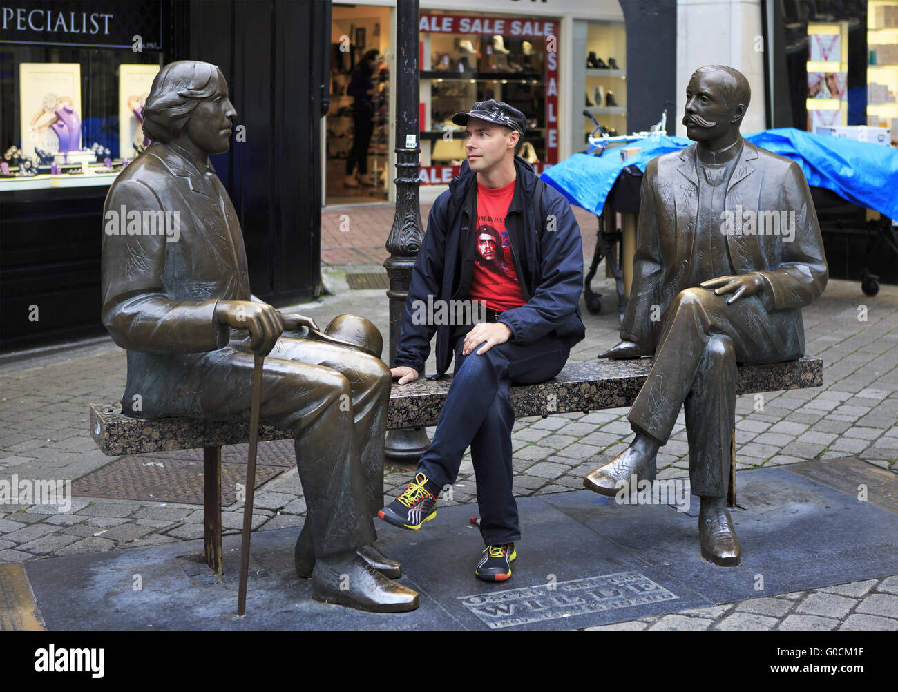 Tourist on the bench with Irish writer Oscar Wilde Stock Photo - Alamy