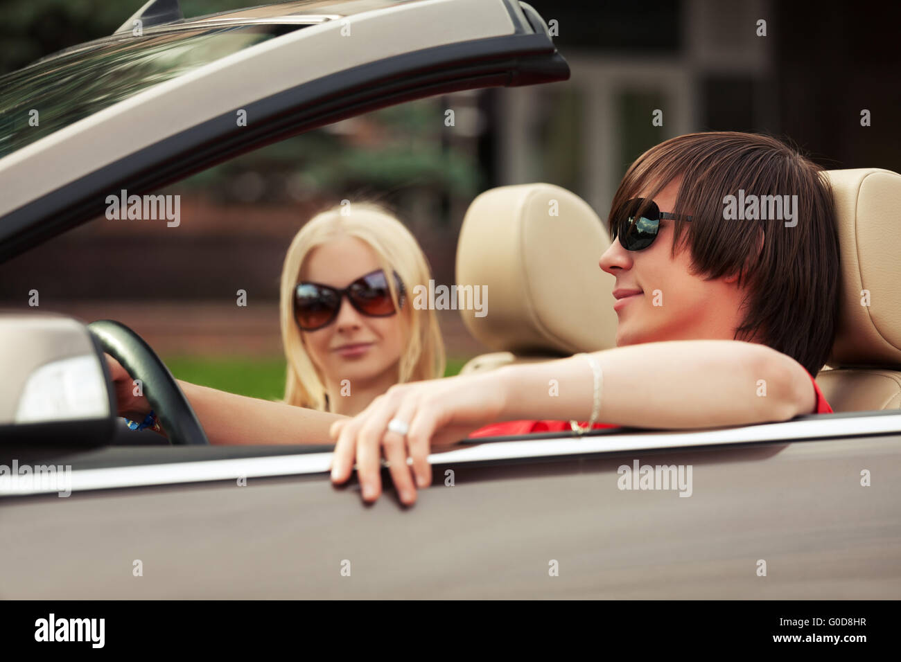 Happy young couple driving convertible car Stock Photo - Alamy