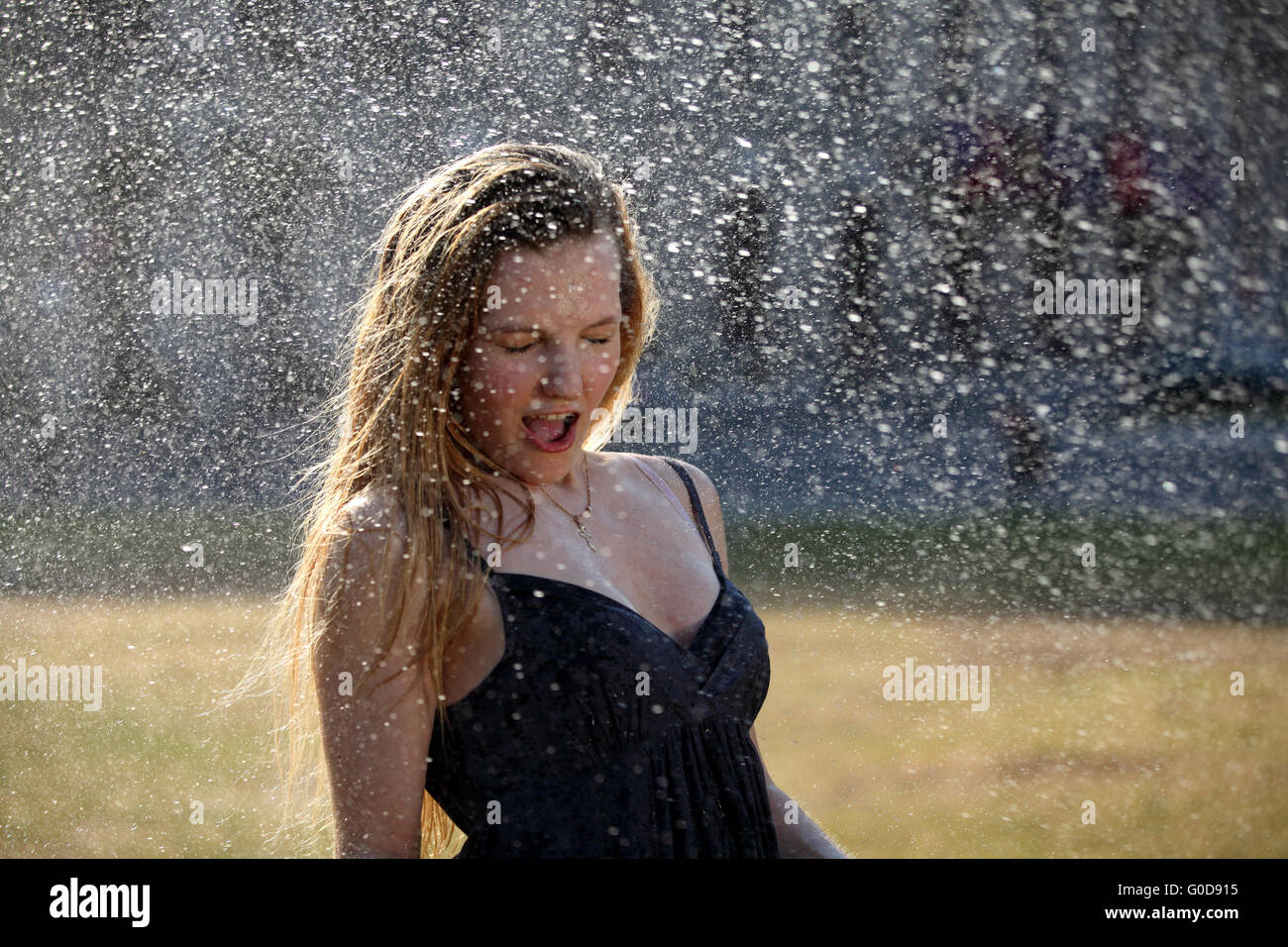 Young woman takes a refreshment under a sprinkler Stock Photo - Alamy