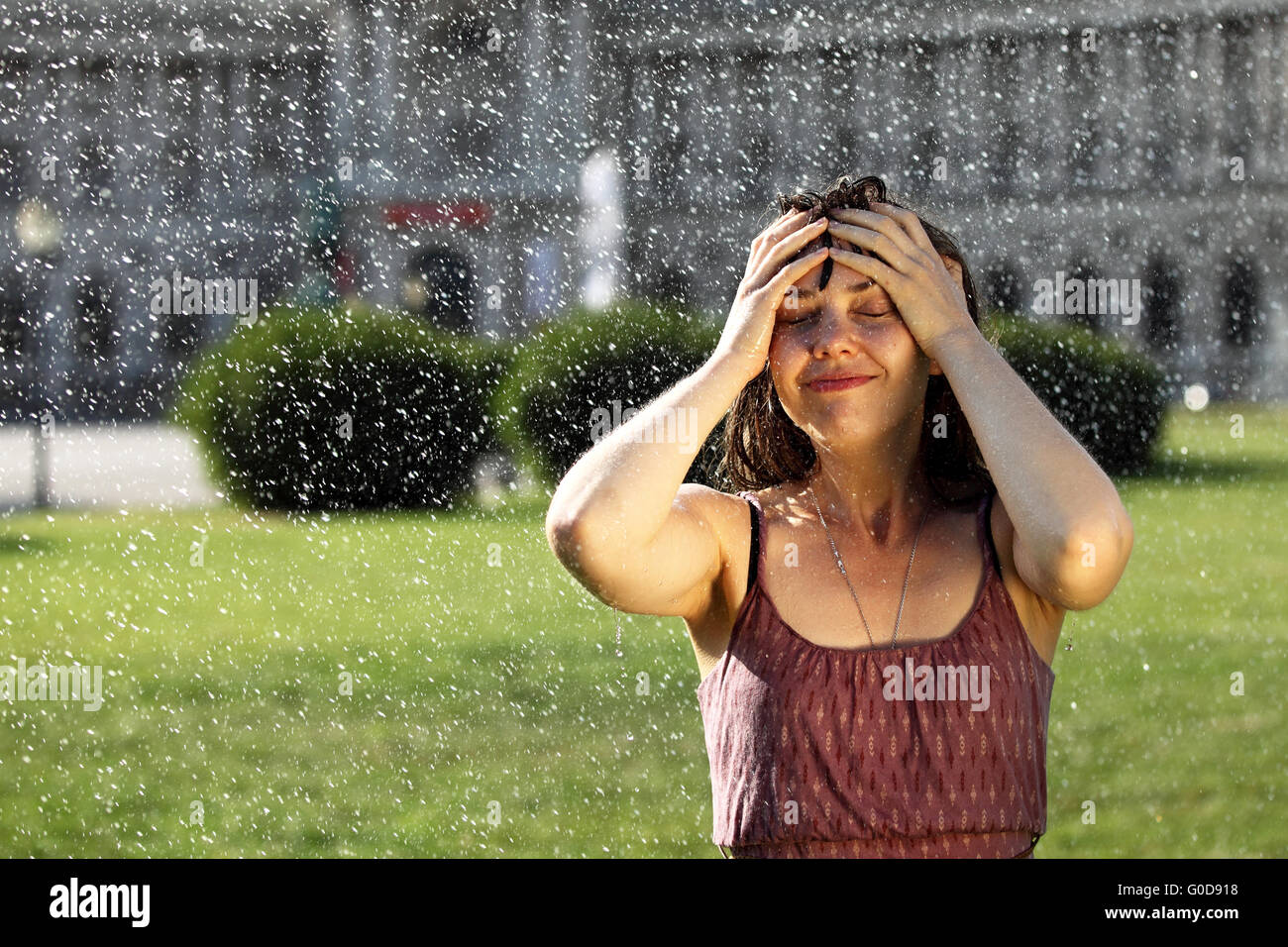 Young woman takes a refreshment under a sprinkler Stock Photo - Alamy