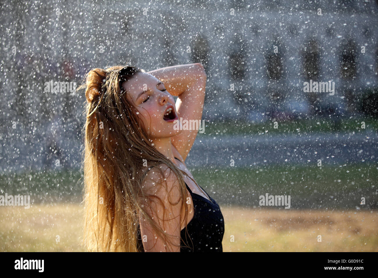 Young woman takes a refreshment under a sprinkler Stock Photo - Alamy