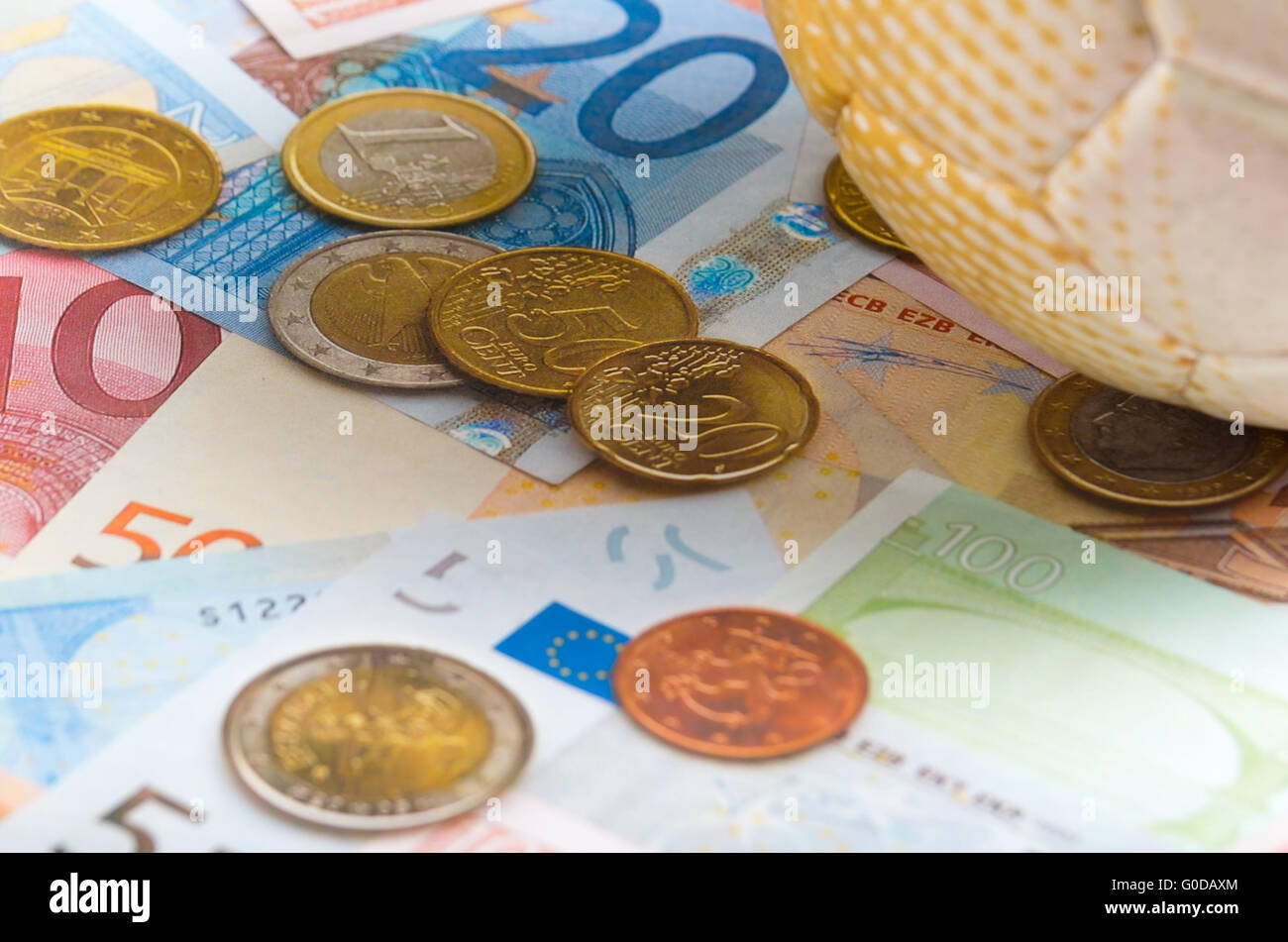 Football sitting on spread out euro money bills and coins, betting ...