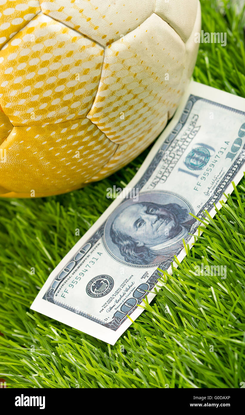 Football sitting on grass surface with dollar bills lying around it ...