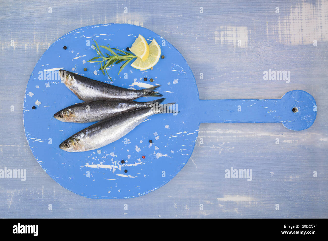 Fresh anchovy fish on blue wooden kitchen board Stock Photo - Alamy