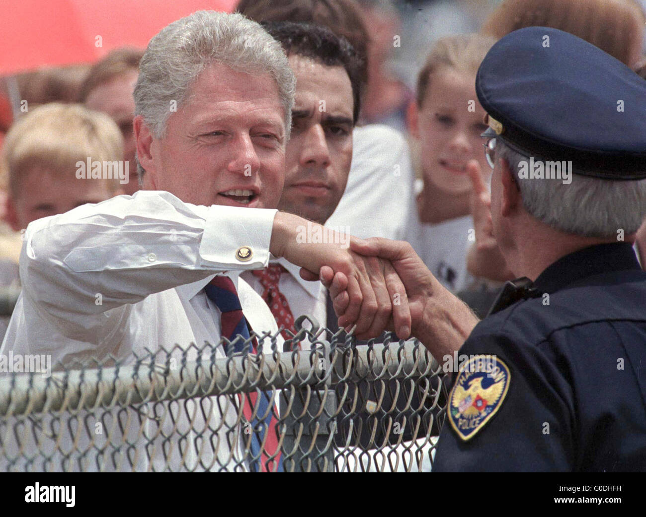 US President Bill Clinton shakes hand over a fence with a Harrison city ...
