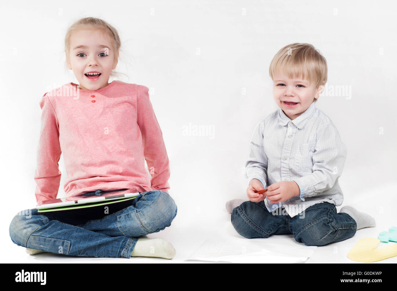 Girl uses a tablet and boy playing with chalk Stock Photo - Alamy