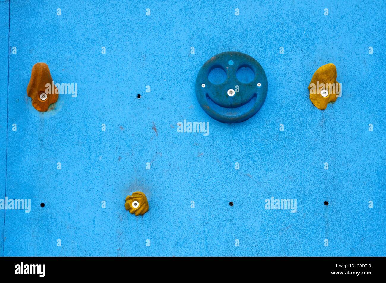 Blue climbing wall background with smiley grip Stock Photo - Alamy