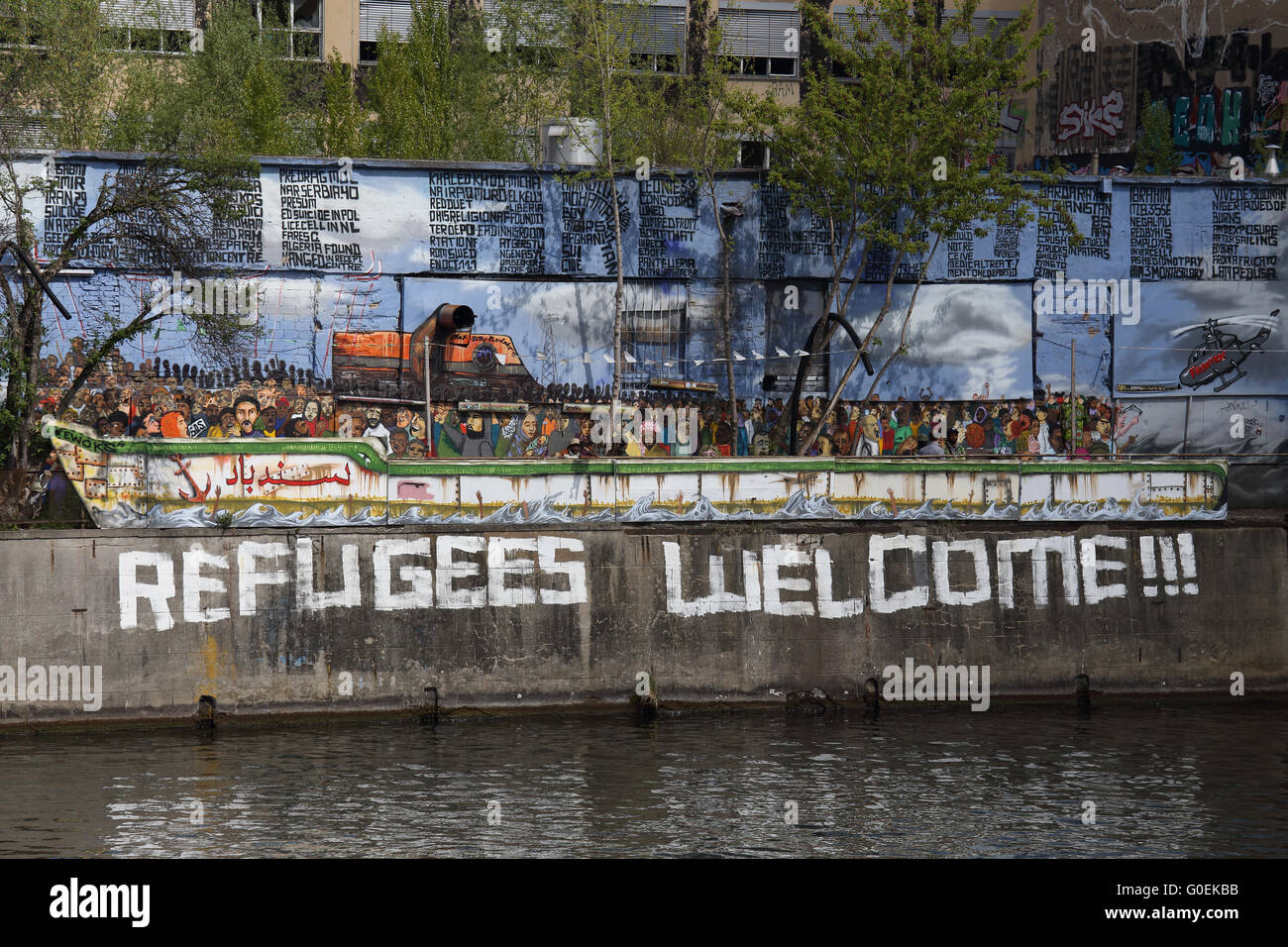 Sign proclaiming "refugees welcome" underneath a mural depicting a boat ...