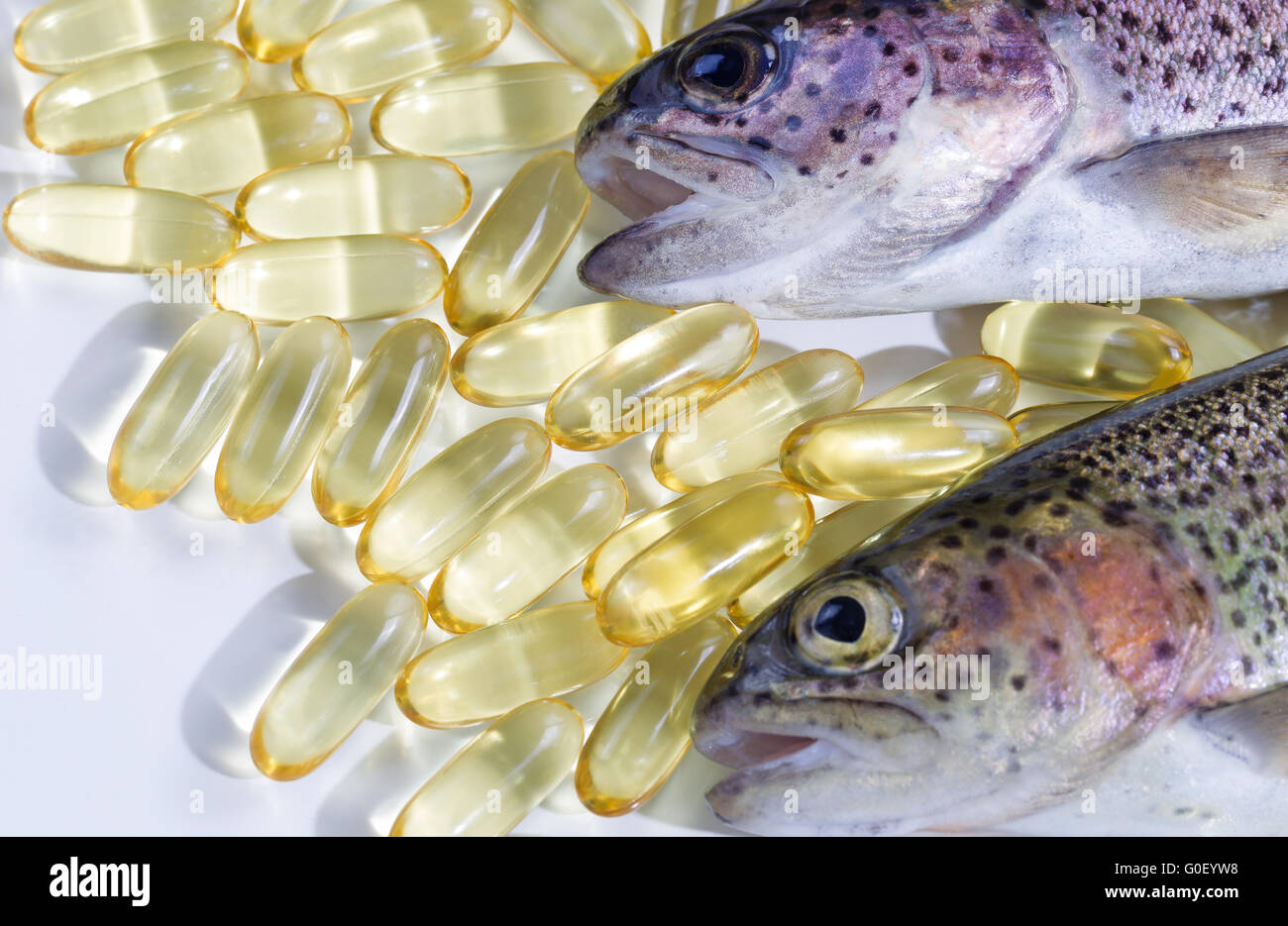 Fish oil capsules with fresh fish on white background Stock Photo - Alamy
