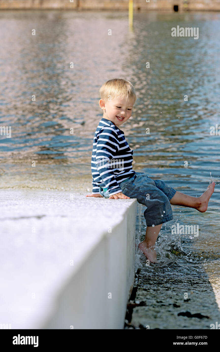 Little preschool boy playing outdoors near water Stock Photo - Alamy