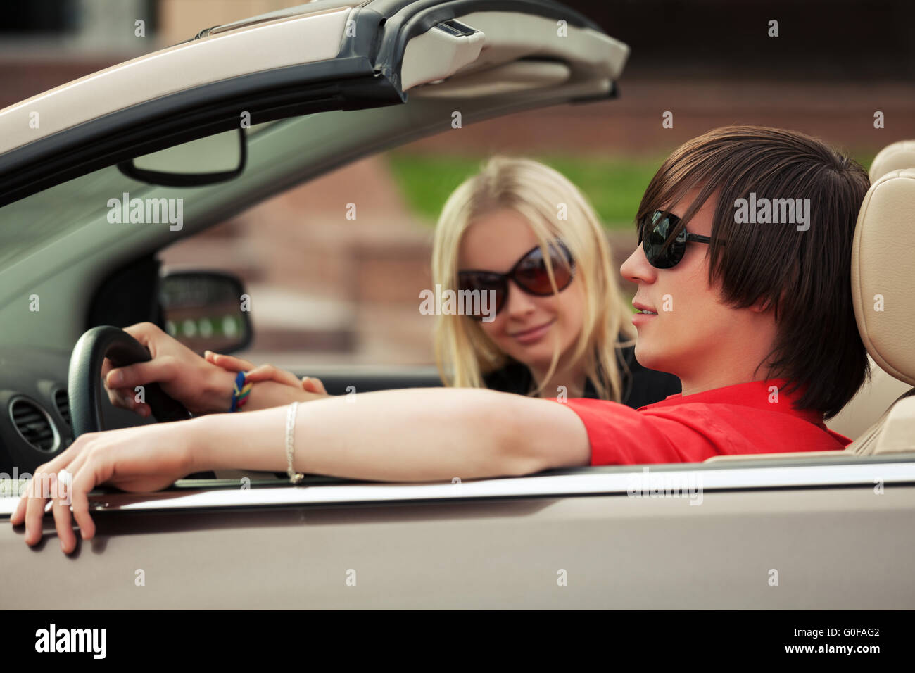 Happy young couple driving convertible car Stock Photo - Alamy