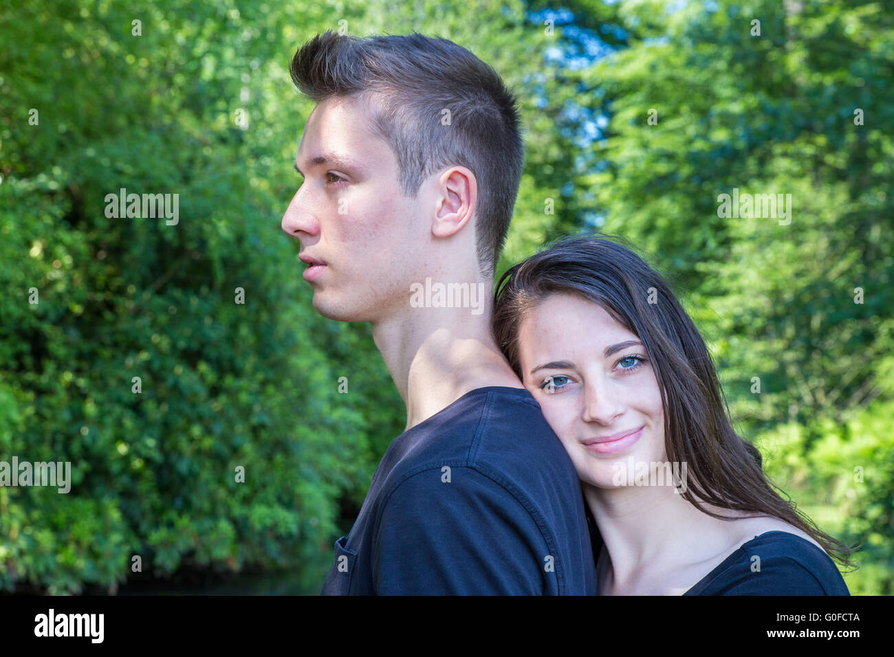 Young attractive woman leaning head on back of man Stock Photo - Alamy