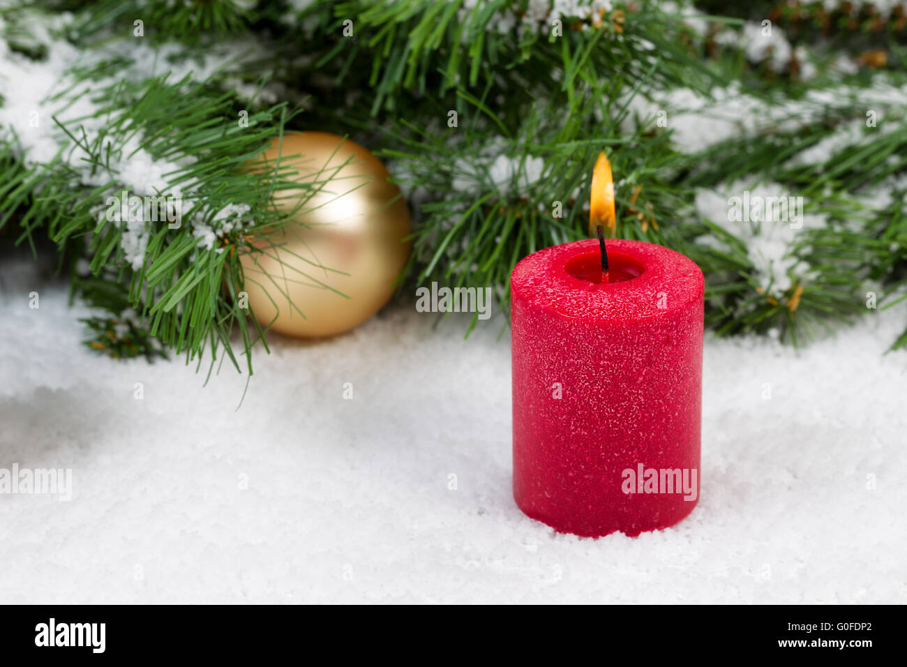 Burning candle with Christmas objects covered with fresh snow Stock ...
