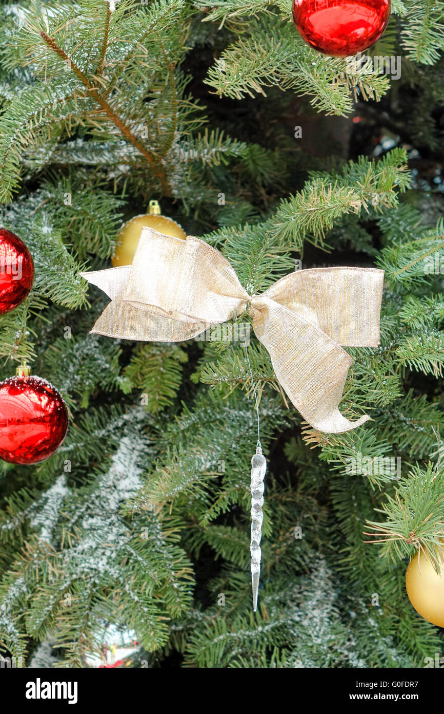 Colorful Christmas ribbon with ornaments hanging from snow covered tree ...
