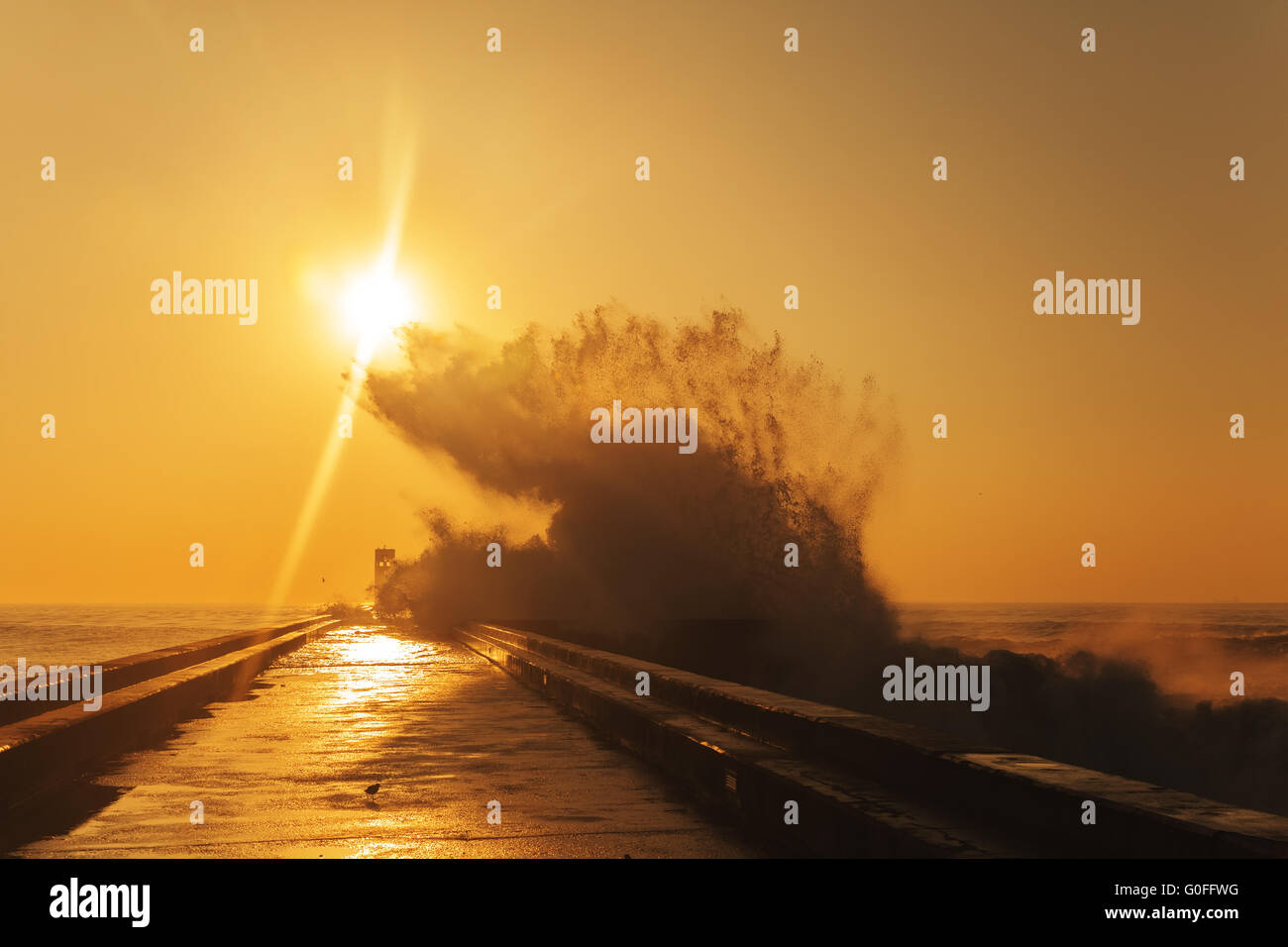 Wave splash at sunset near lighthouse Stock Photo - Alamy
