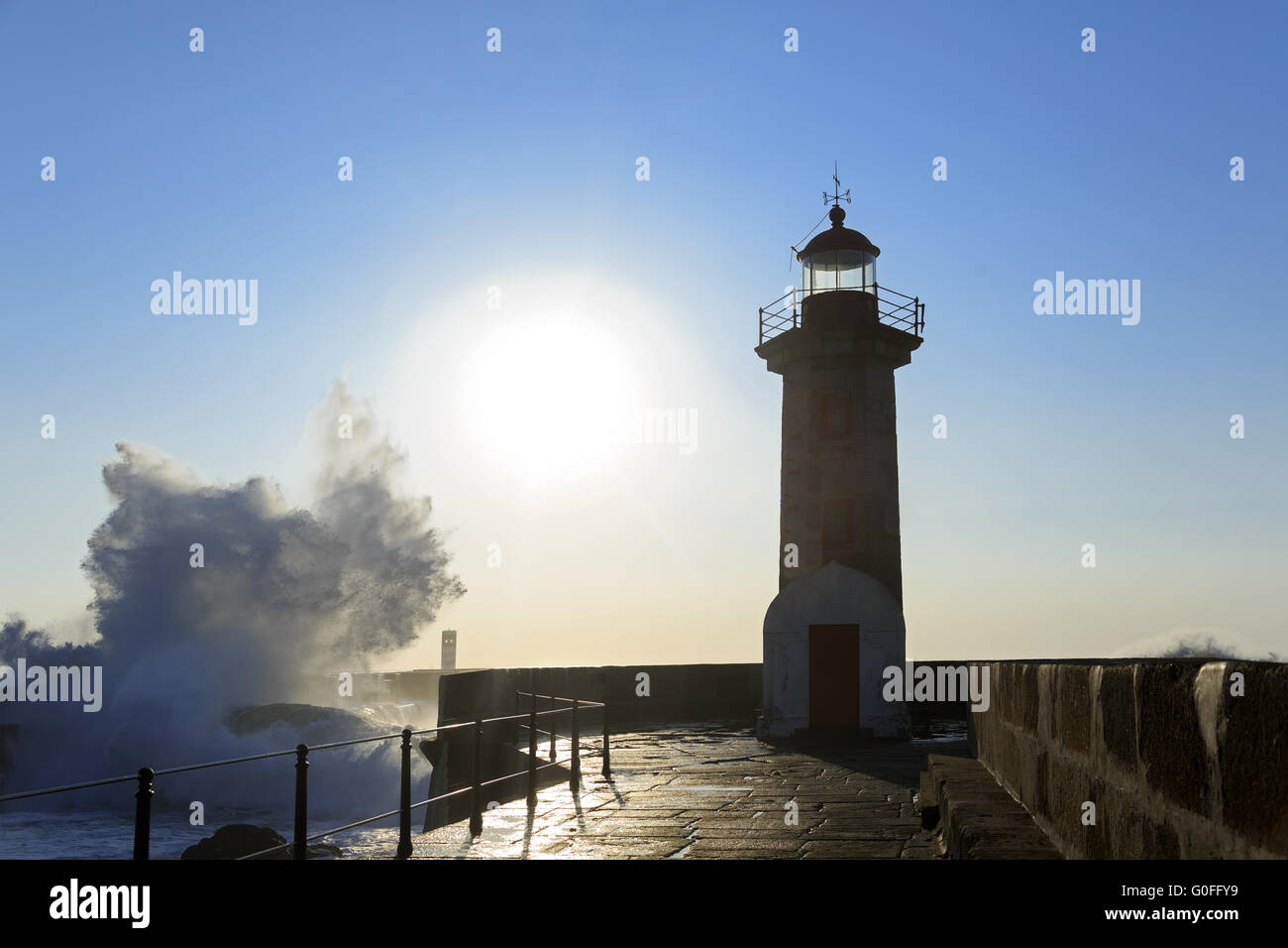 Wave splash at sunset near lighthouse Stock Photo - Alamy