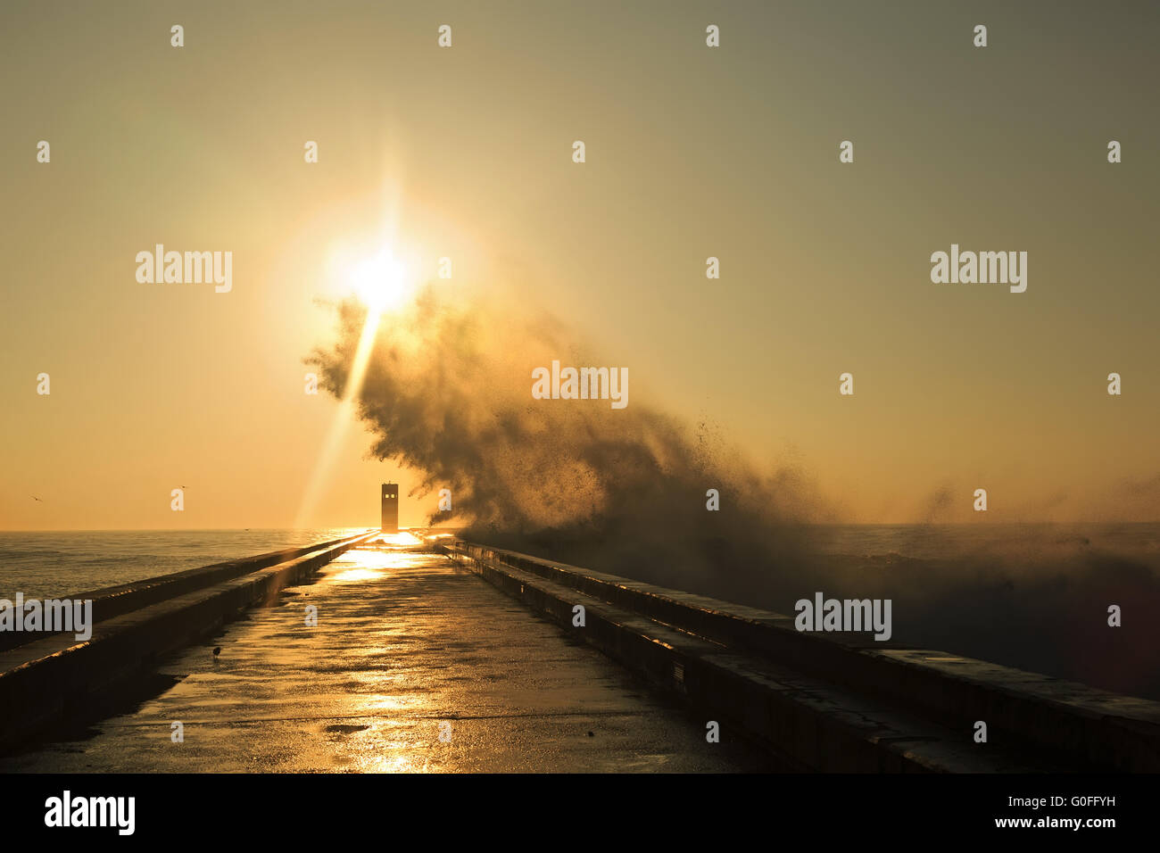 Wave splash at sunset near lighthouse Stock Photo - Alamy
