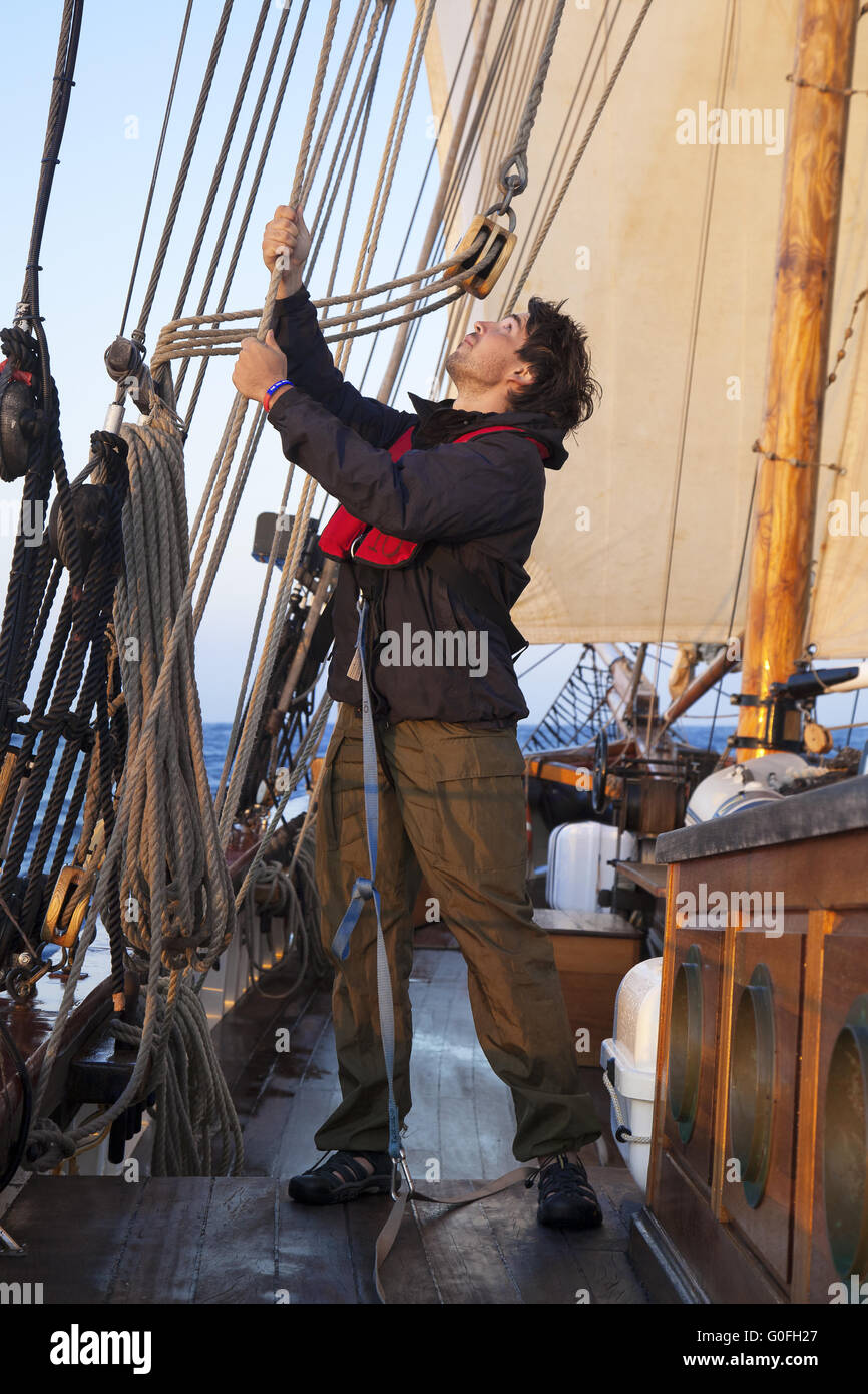 Young sailor on a ship's deck hoisting a sail Stock Photo - Alamy