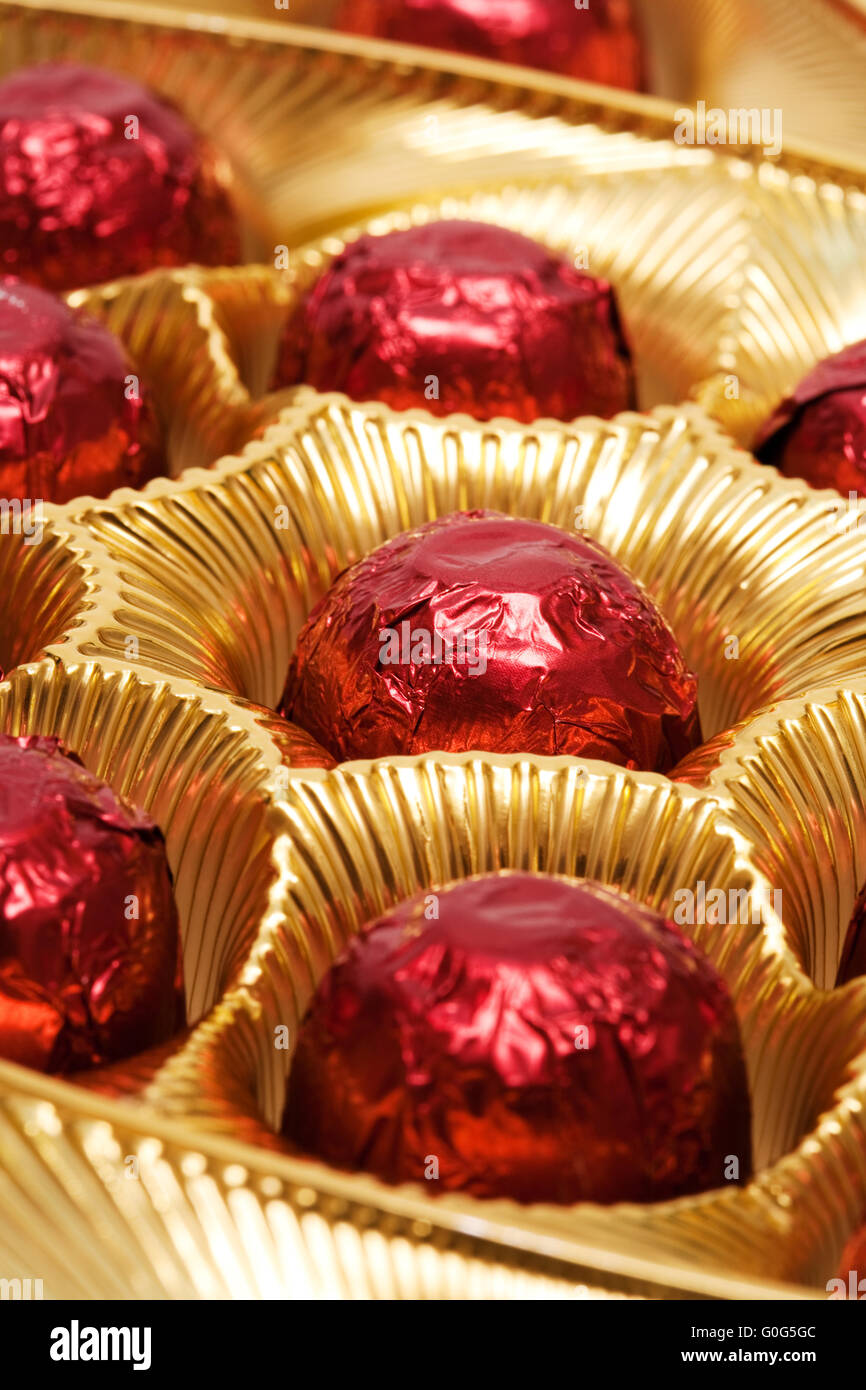 Chocolates in a red foil in a beautiful gold box Stock Photo - Alamy