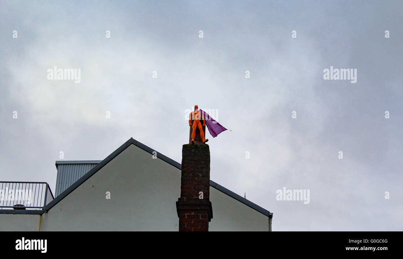 A caped superhero figure (toy) stands on a chimney stack above ...