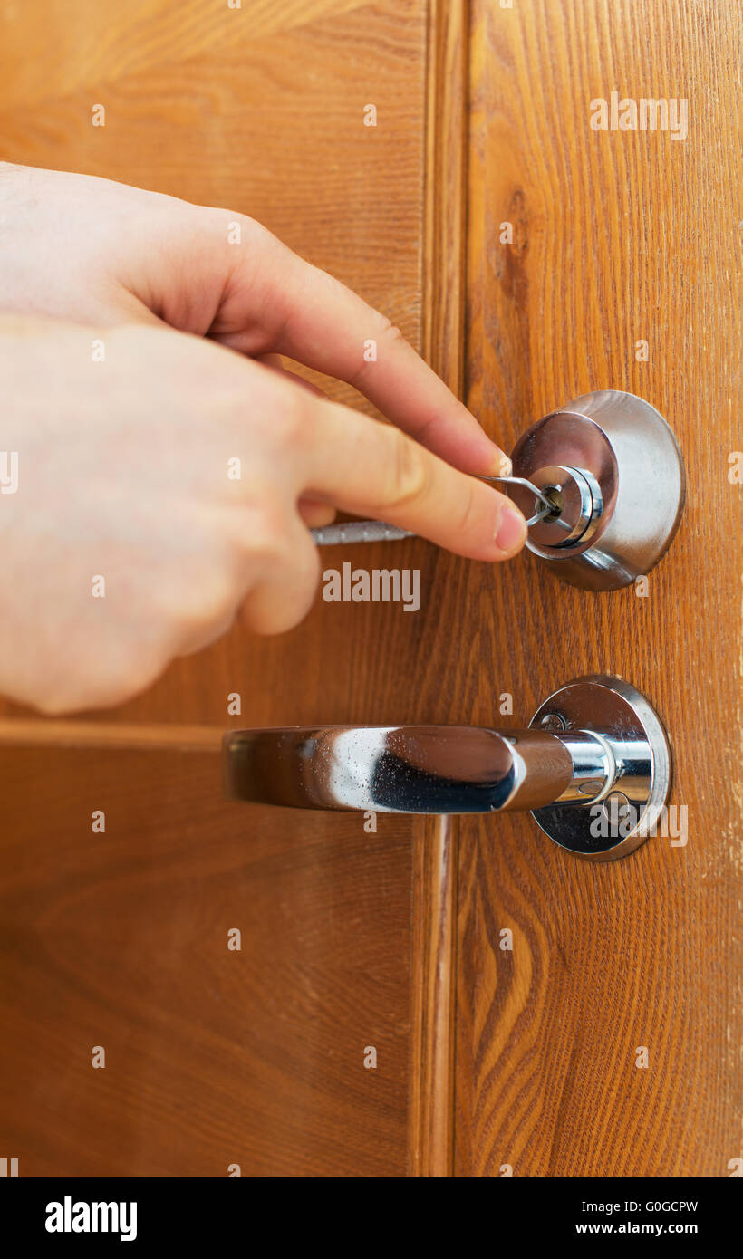 Man's hand opening door with lock picker Stock Photo - Alamy
