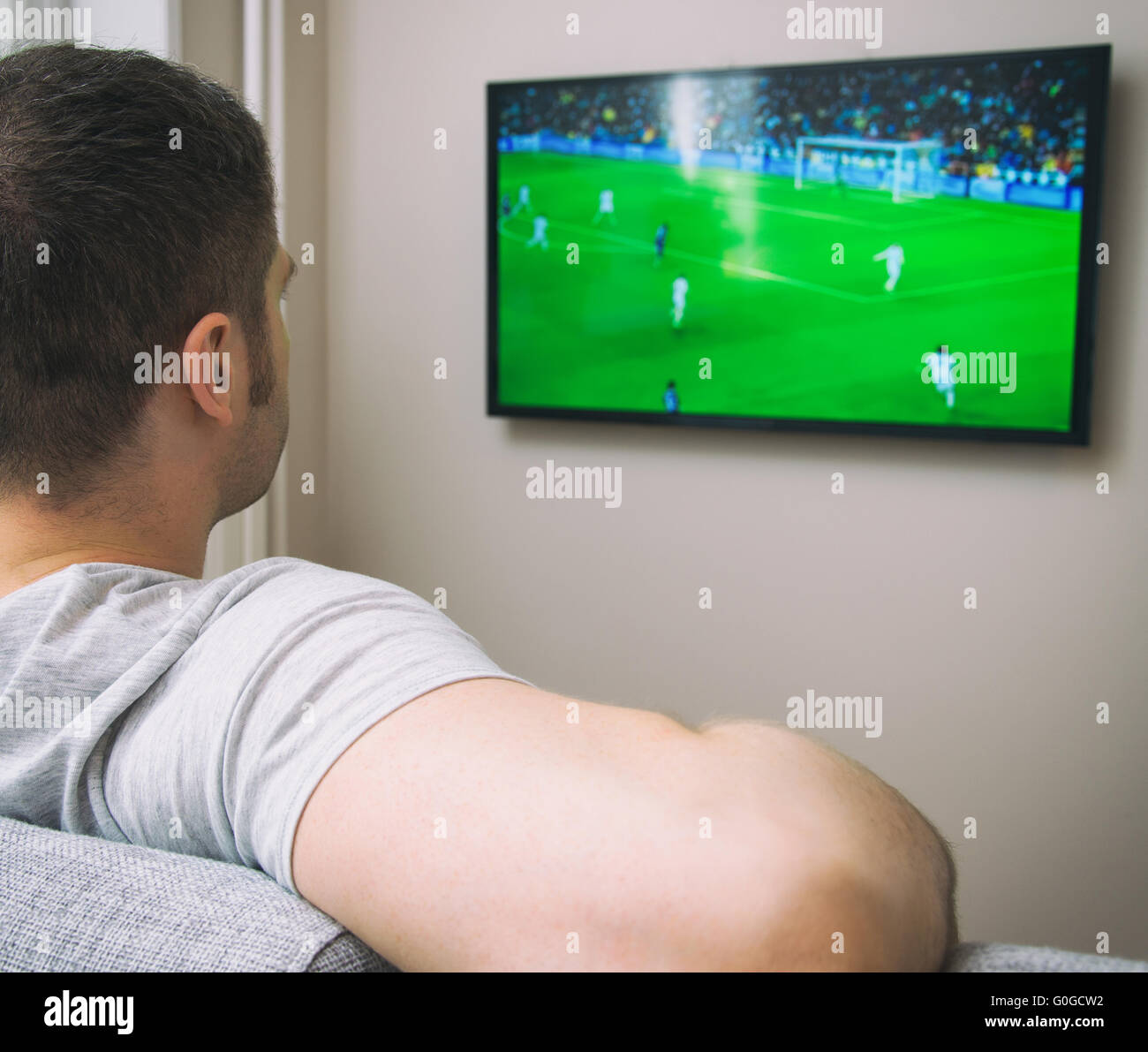 Man watching football match on television at home Stock Photo - Alamy