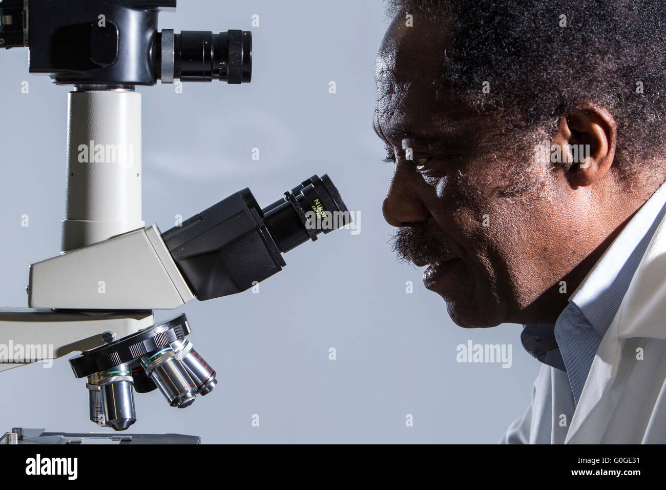 Microbiologist looking through microscope Stock Photo - Alamy