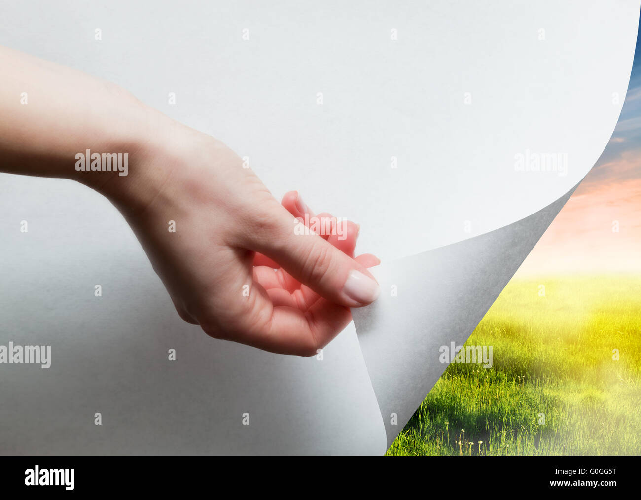 Hand pulling a bottom paper corner to uncover Stock Photo - Alamy