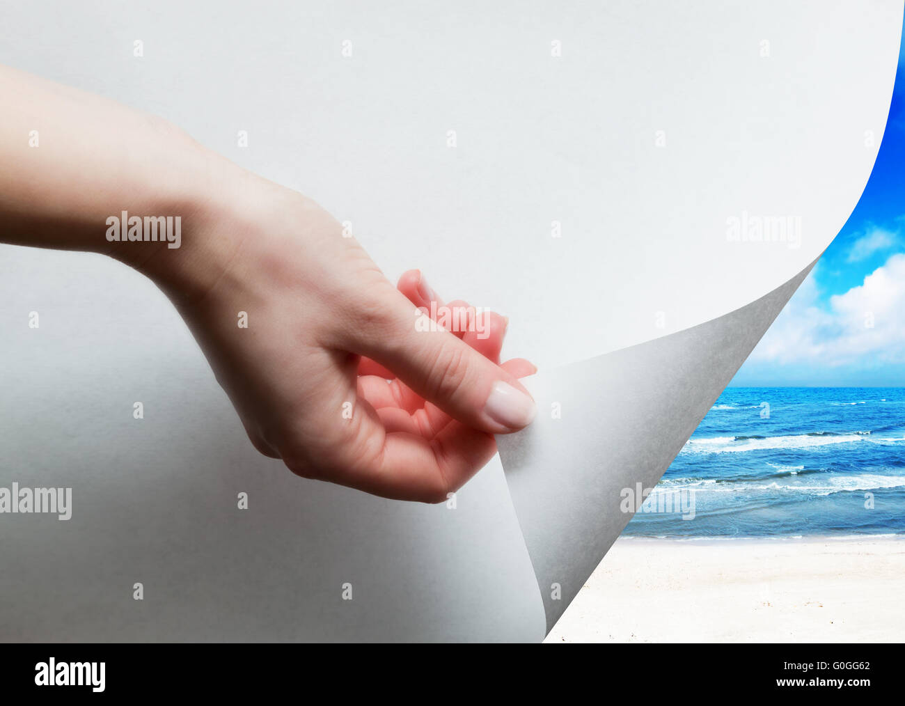 Hand pulling a bottom paper corner to uncover Stock Photo - Alamy