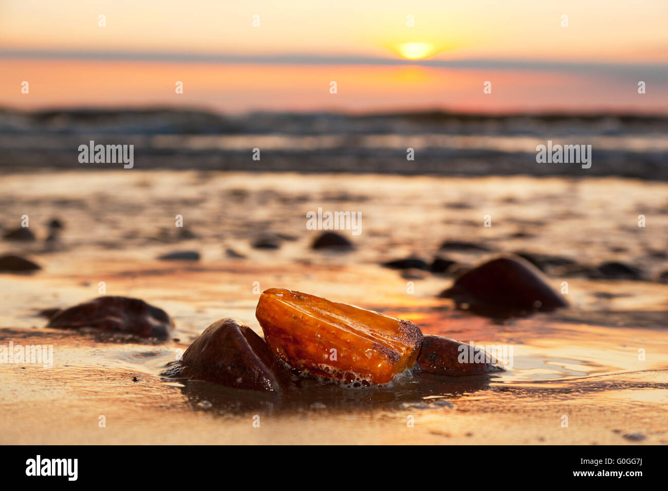 Amber stone on the beach at sunset. Precious gem Stock Photo - Alamy