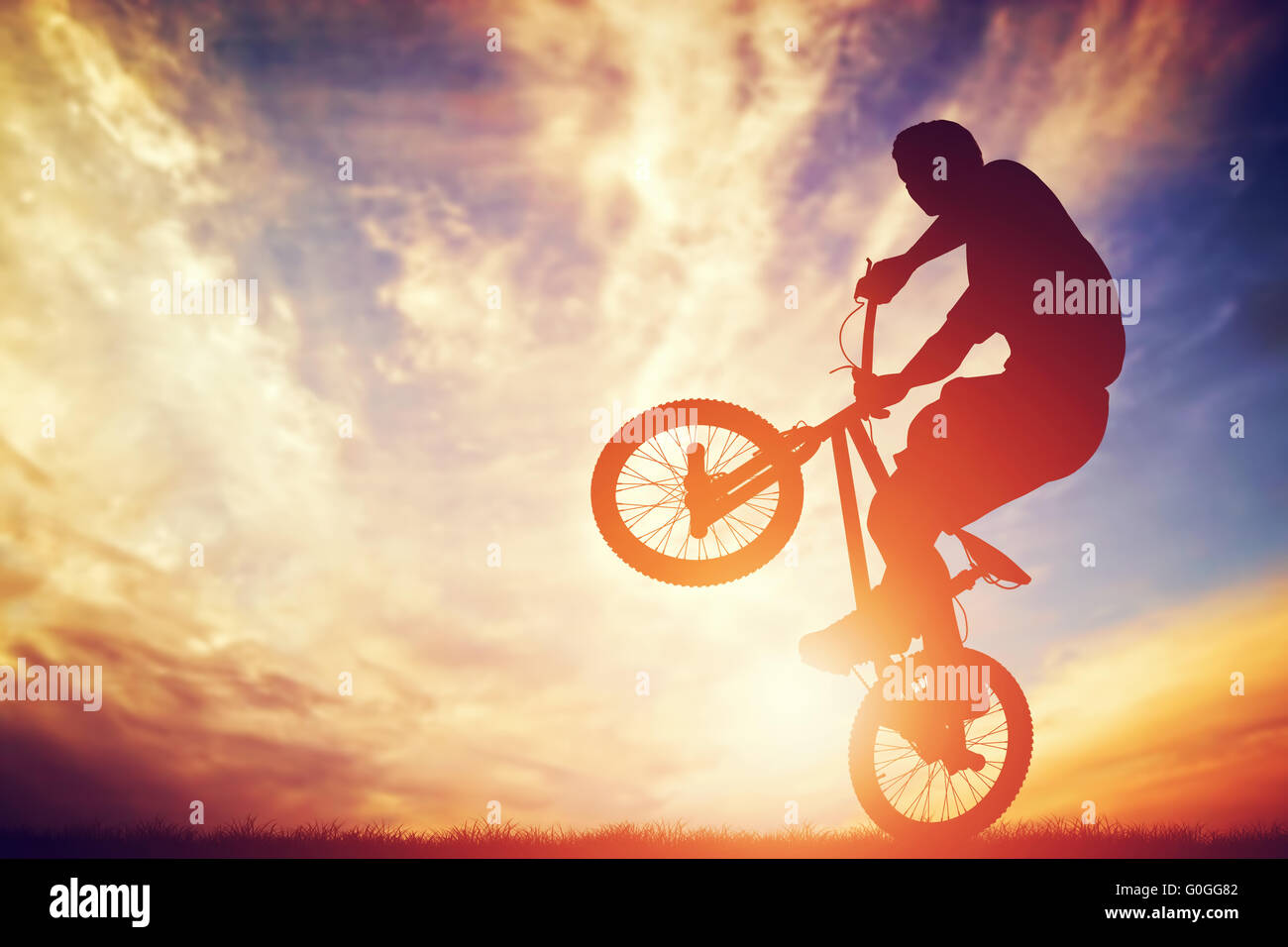 Man riding a bmx bike performing a trick against sunset sky. Extreme ...